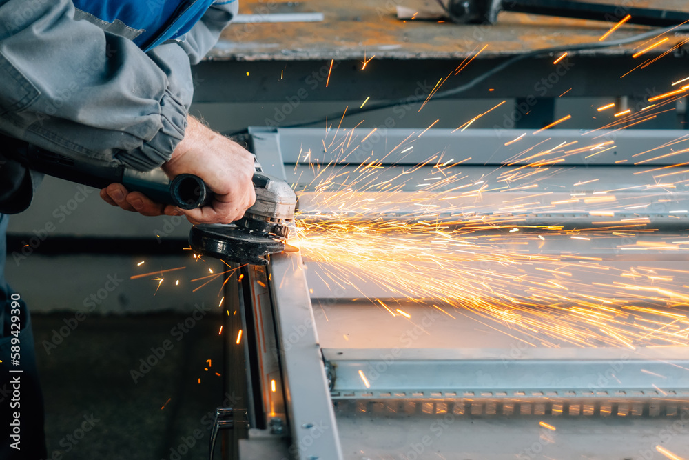 Hands of worker with close-up grinder during workflow. Man grinds ...
