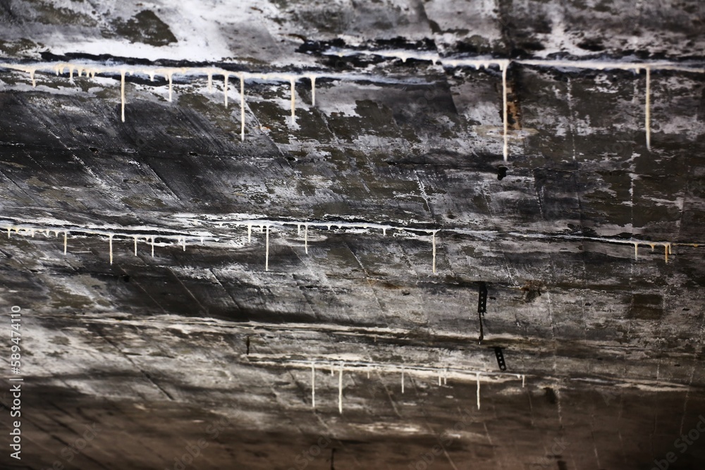 Cracked concrete ceiling, water is forming stalactites from washout of ...