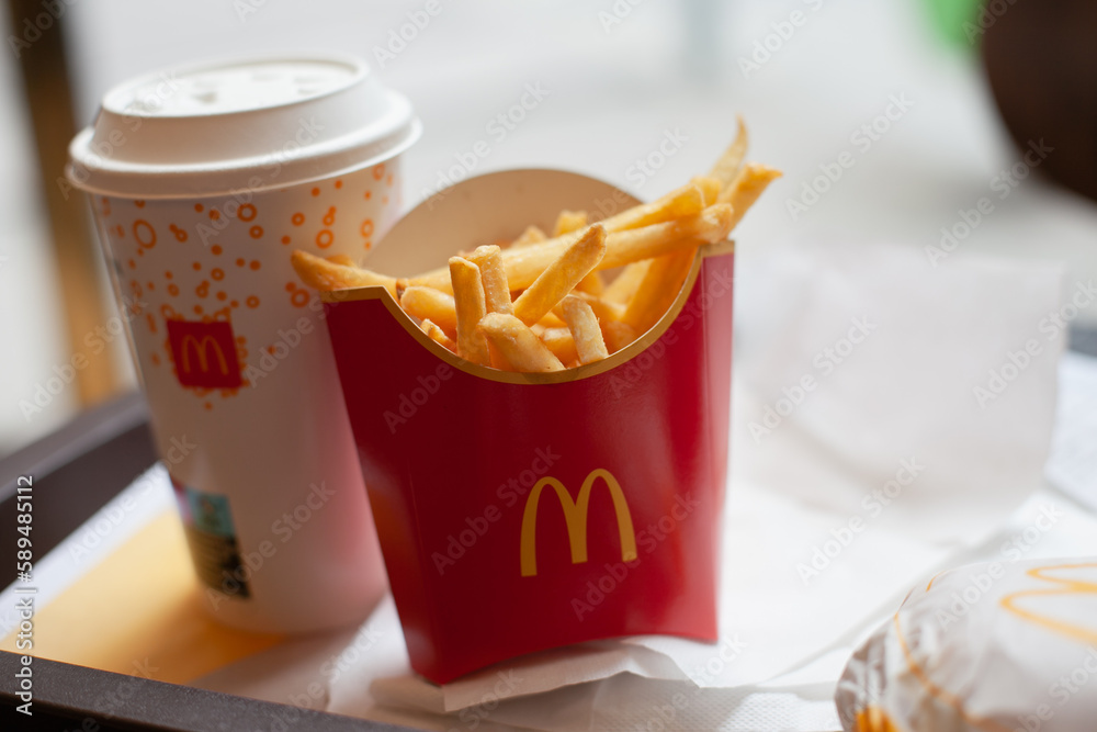French fries and soda from McDonalds in branded packaging closeup at the restaurant. Eating fast ...