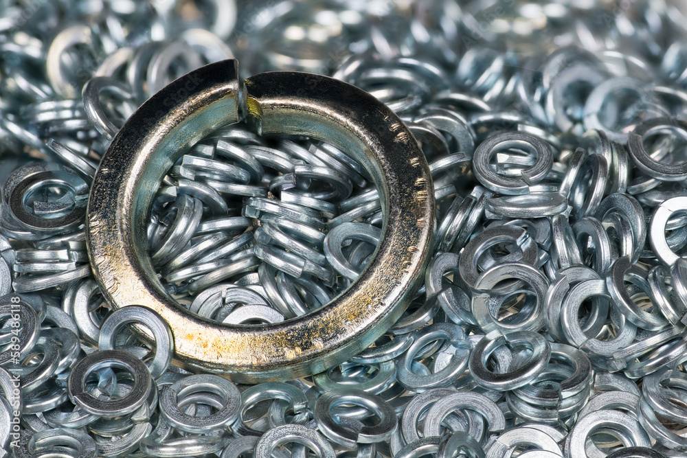 Closeup of big steel spring lock washer on texture of small stainless ...
