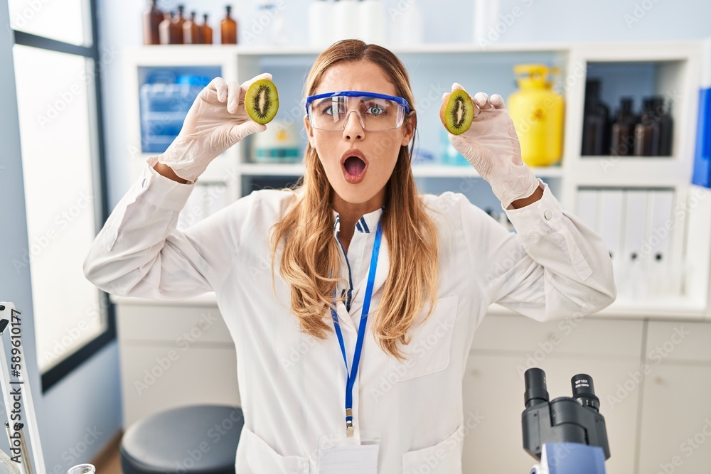 Young blonde scientist woman working with food at laboratory afraid and ...