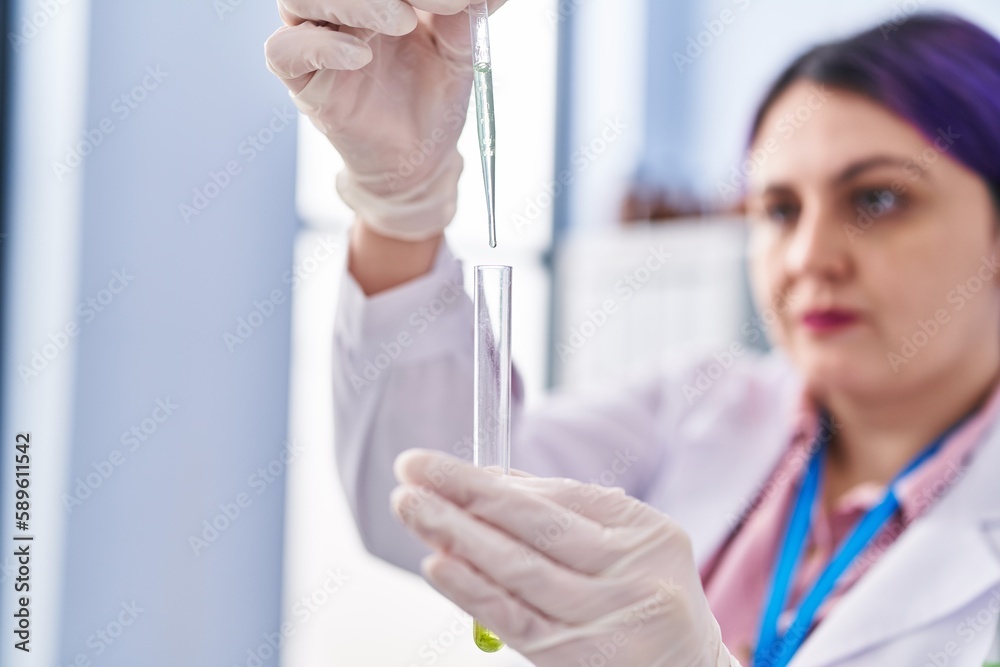 Young beautiful plus size woman scientist pouring liquid on test tube ...