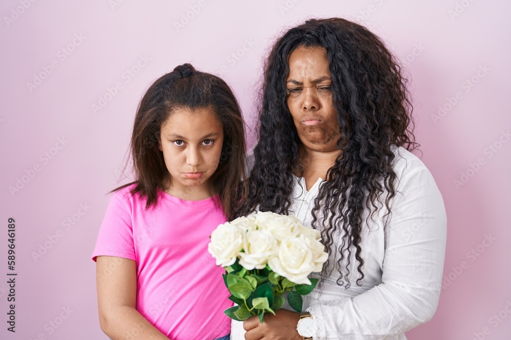 Mother and young daughter holding bouquet of white flowers depressed ...