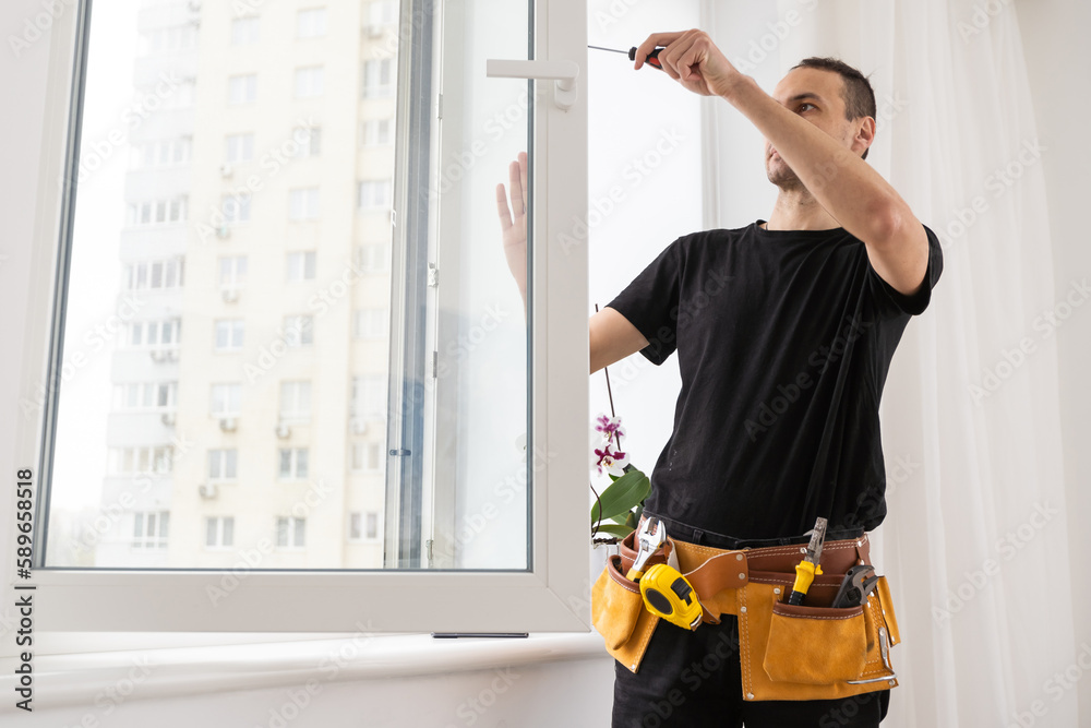 Handsome young man installing bay window in a new house construction ...