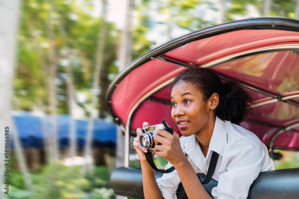 happy black traveler girl using camera outside tuk tuk ride. solo ...