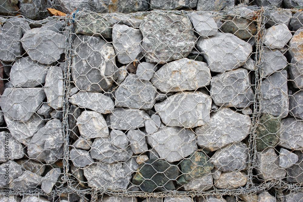 Workers install wire mesh to prevent rock and soil erosion in roadside ...