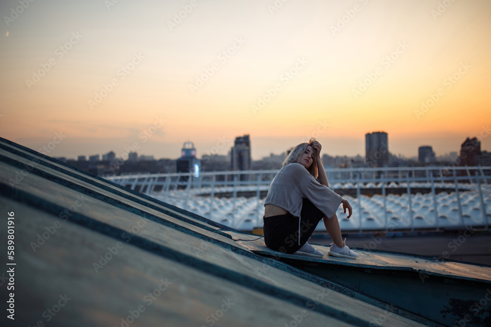 Foto de Beautiful woman on the rooftop posing at sunset. A young woman ...