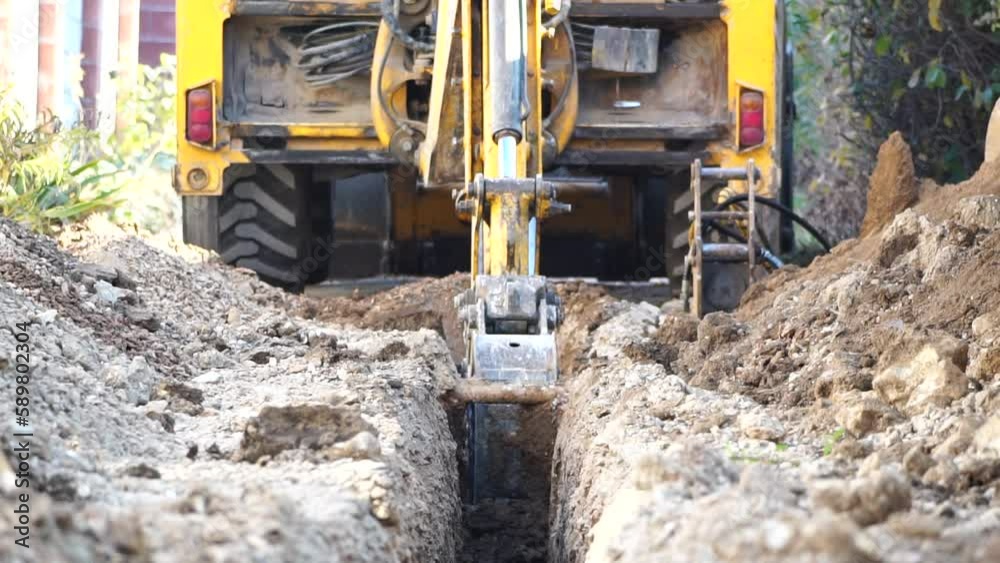 Excavator digs a trench to lay pipes. Close up of an excavator digging ...
