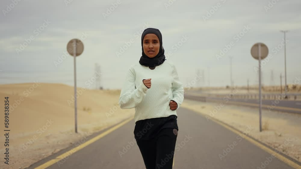 Beautiful female runner wearing sport abaya running in the desert in ...