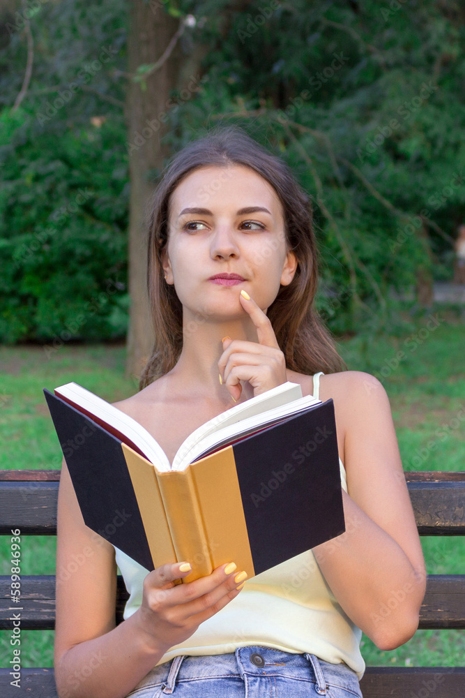 Beautiful woman is reading a book and thinking about something on the ...