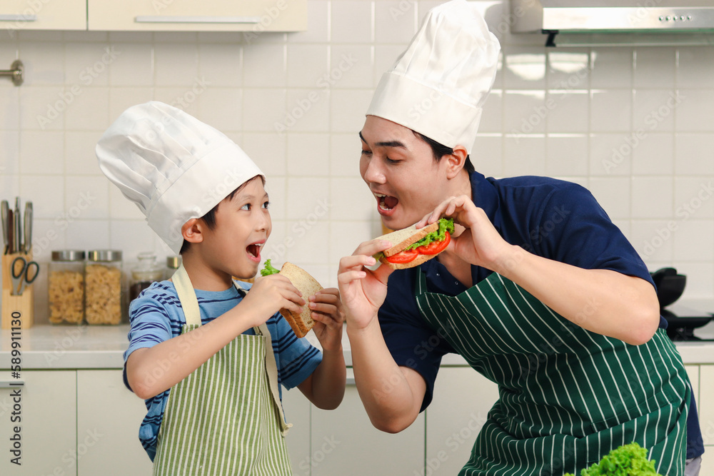 Happy Asian father and son kid with apron and chef hat cooking meal ...