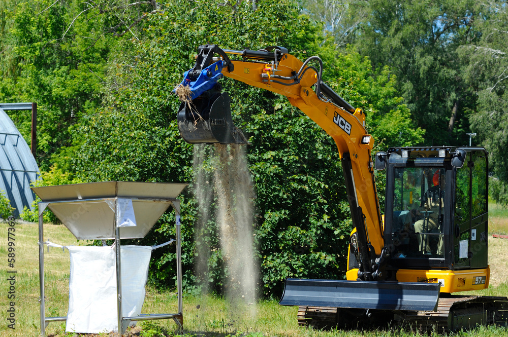 Bobcat JCB loading sand into a radioactive waste storage container ...