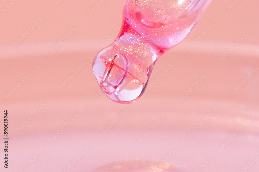 Pipette with dripping pink liquid. Or liquid rose gold. Close-up. On a ...