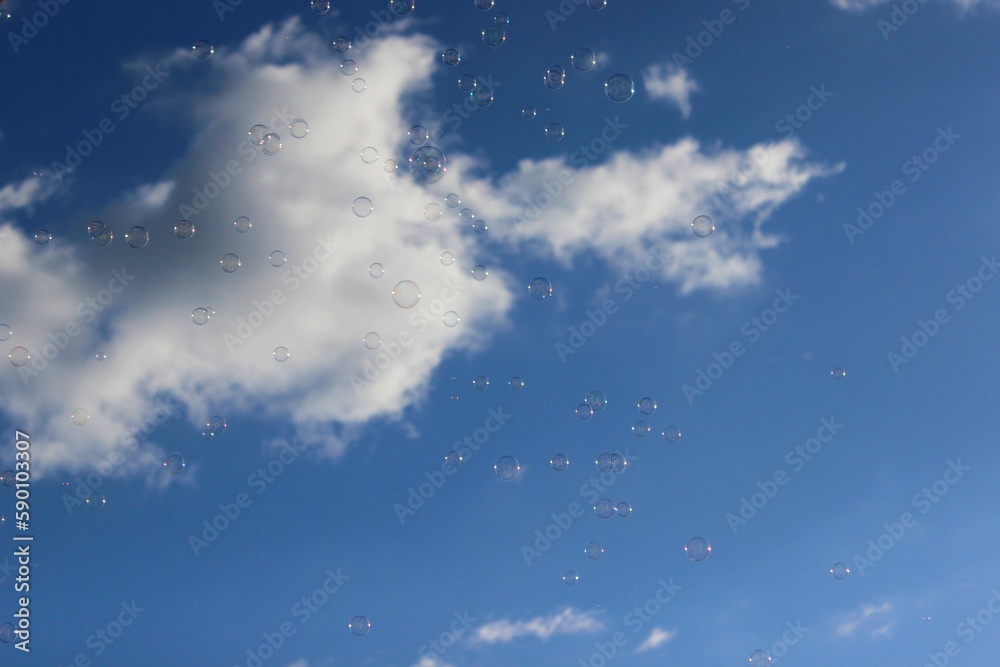 Hundreds of bubbles flying in the air. Blue sky and a big white cloud ...