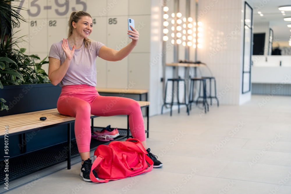Foto de Beautiful smiling athletic young woman sitting on bench in ...