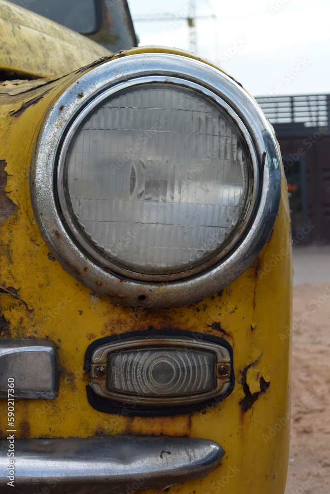 Details of an old rusty dirty yellow vintage retro car. Front round ...