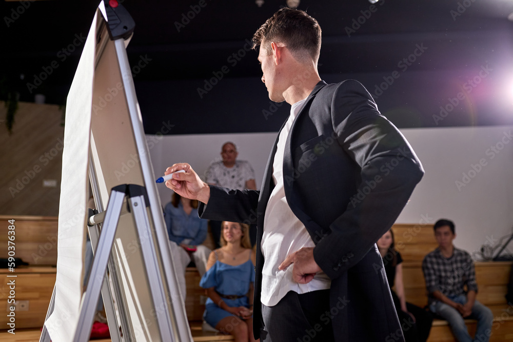 Male speaker giving presentation to students in hall at university ...