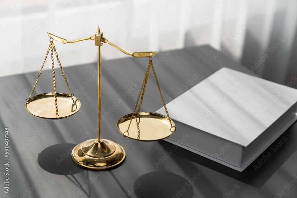 Shiny golden balanced scale and law book on desk in law school as ...