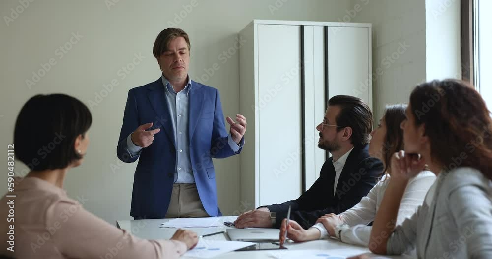 Mature business group leader man speaking at team, talking to employees ...