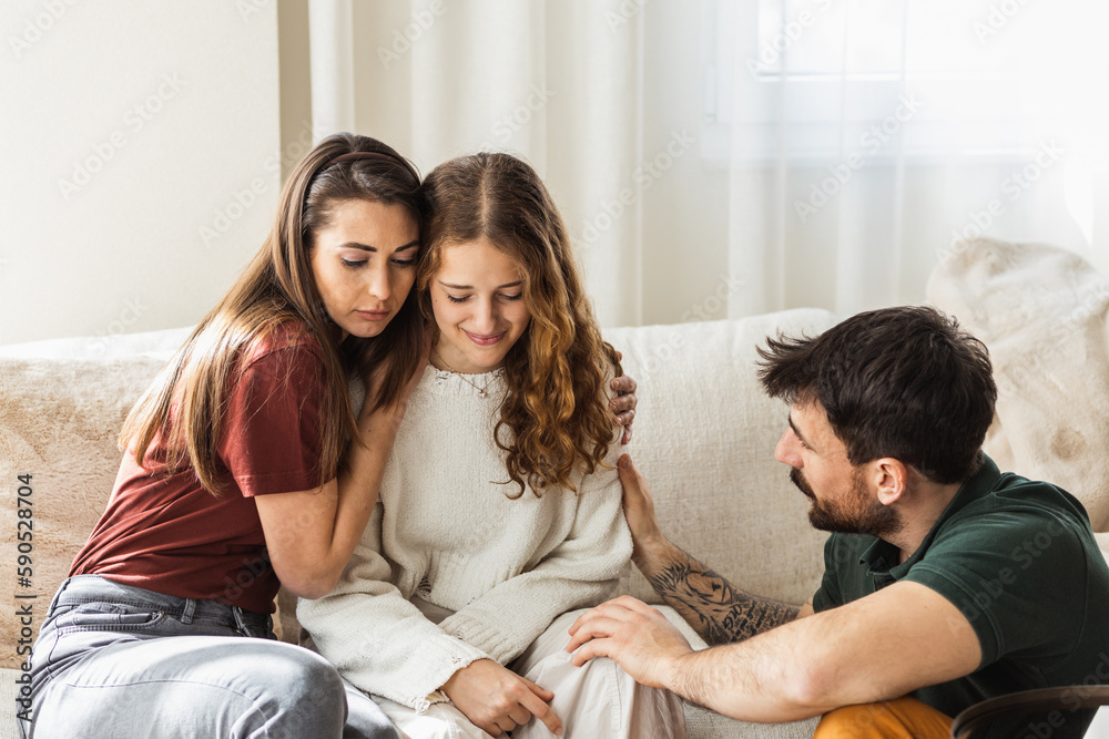 Young parents hug and comfort their teenage daughter while she is ...