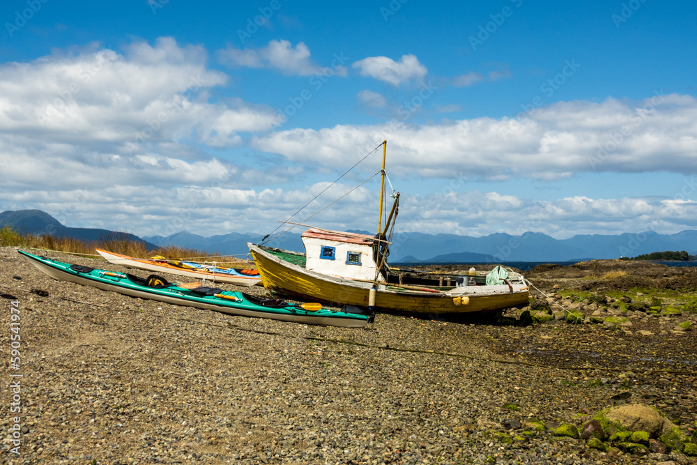 sea kayaks and a small artisanal subsistence fishing boat on a beach in ...