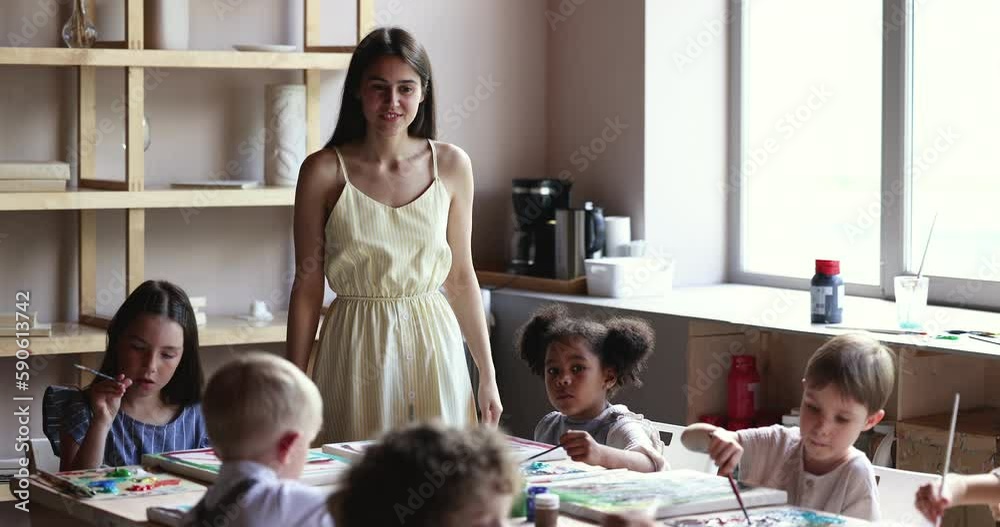 Young artistic master girl teaching little children in studio, talking ...