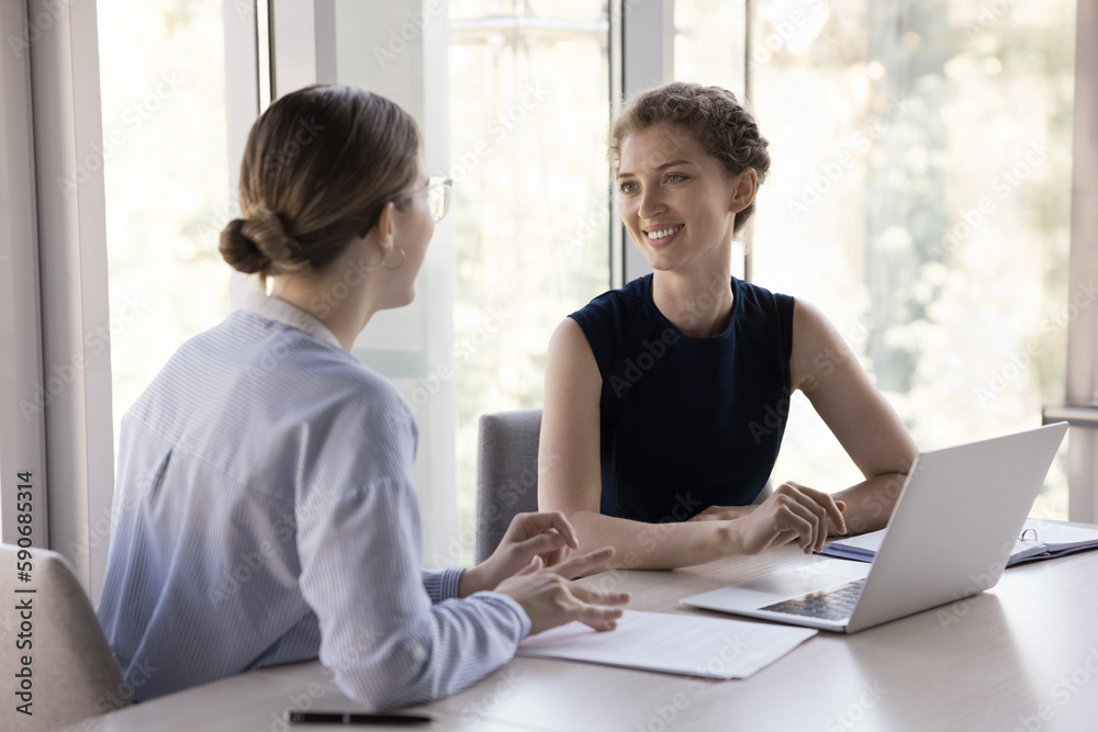 Zdjęcie Stock: Cheerful young office employees women talking at laptop ...