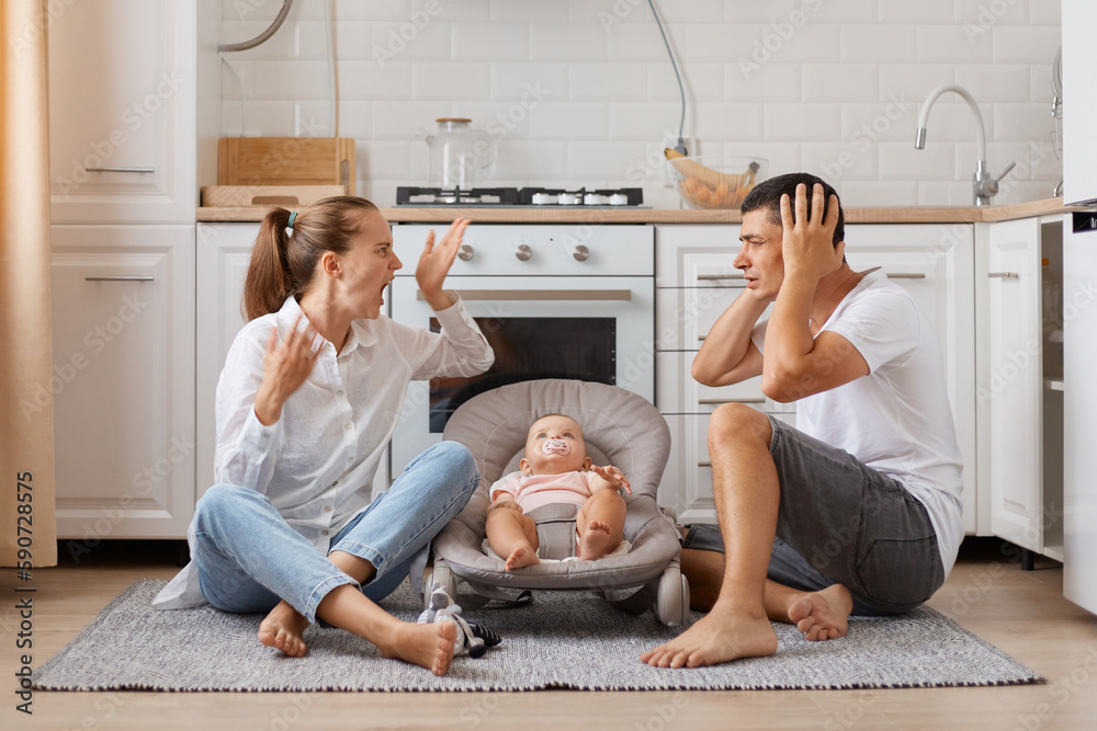 Despair family with little child sitting on floor in modern kitchen ...