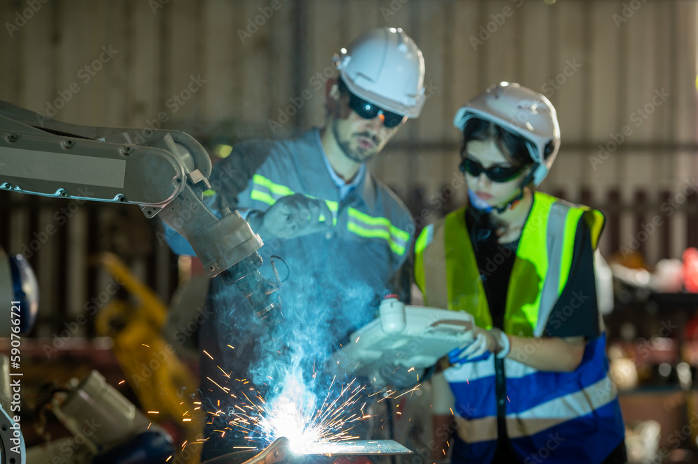 Engineer control robot arm machine welding steel, worker using forcing ...