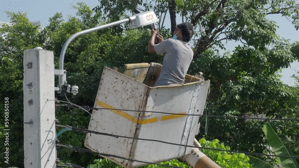 Worker on height lifting platform installing new street light bulb ...