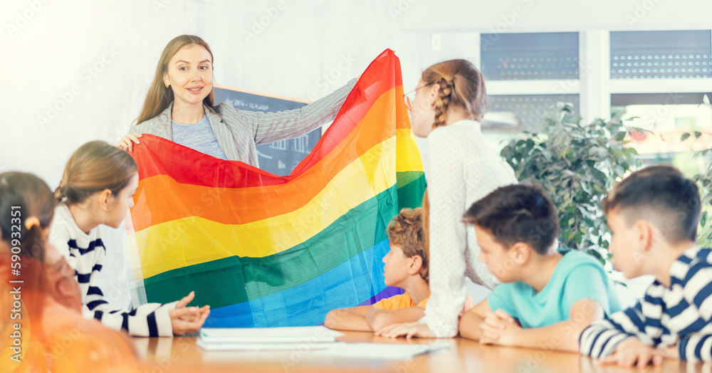 Positive female teacher explaining lgbt theme to children during lesson ...