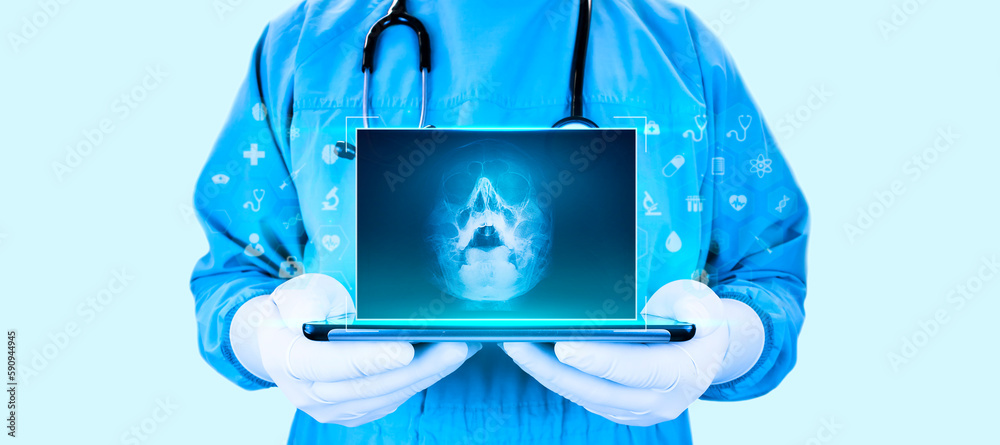 Doctor with tablet isolated observes and analyzes a skull x-ray, nose ...