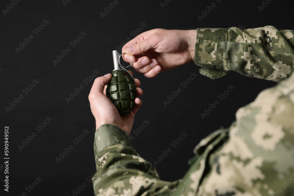 Soldier pulling safety pin out of hand grenade on black background ...