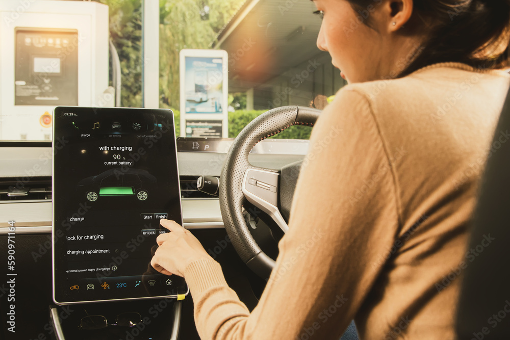 Back view young woman asian driving an EV electric car sit in the ...
