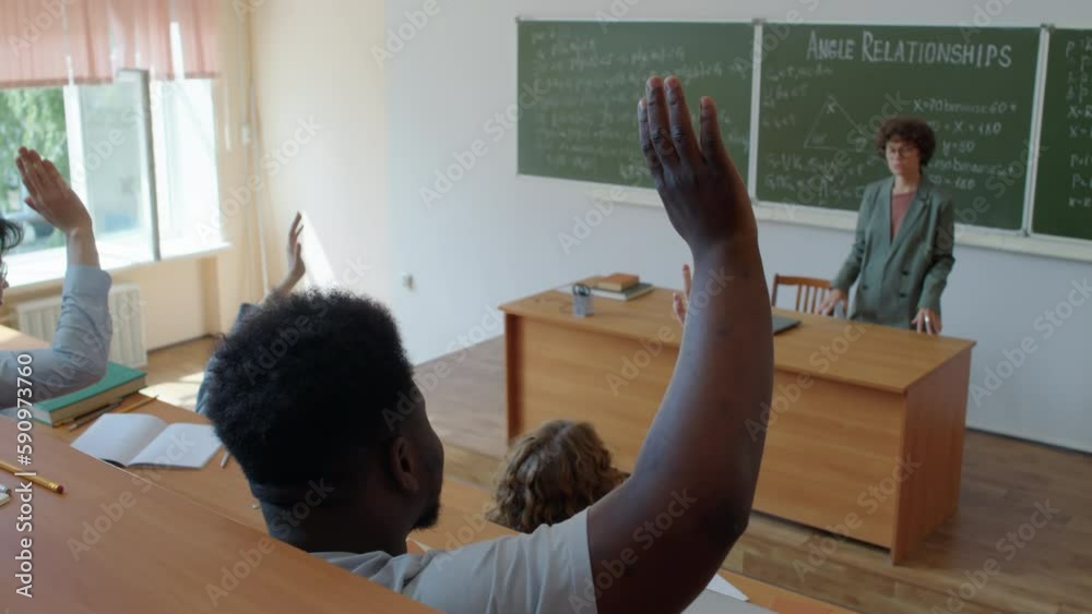 Group of ethnically diverse college students raising their hands to ask ...