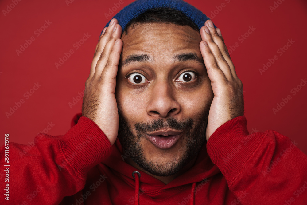 Amazed indian man screaming and touching his head isolated over red ...