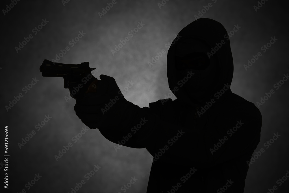 Mysterious man wearing black hoodie holding a pistol, shooting with a ...