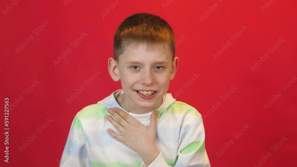 caucasian boy 9 years old laughs looks at the camera, red background ...