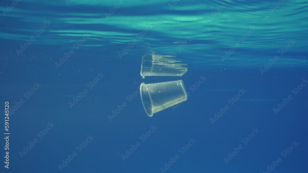 Close-up of plastic cup slowly floating underwater, slow motion ...