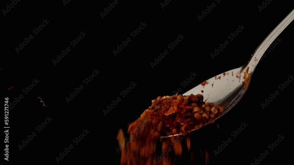 table silver spoon of red seasoning spices mix falling out of the frame ...