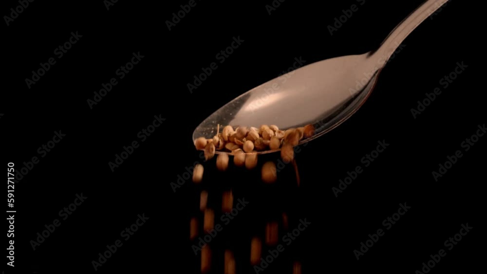 table silver spoon of grinded coriander falling out of the frame with ...