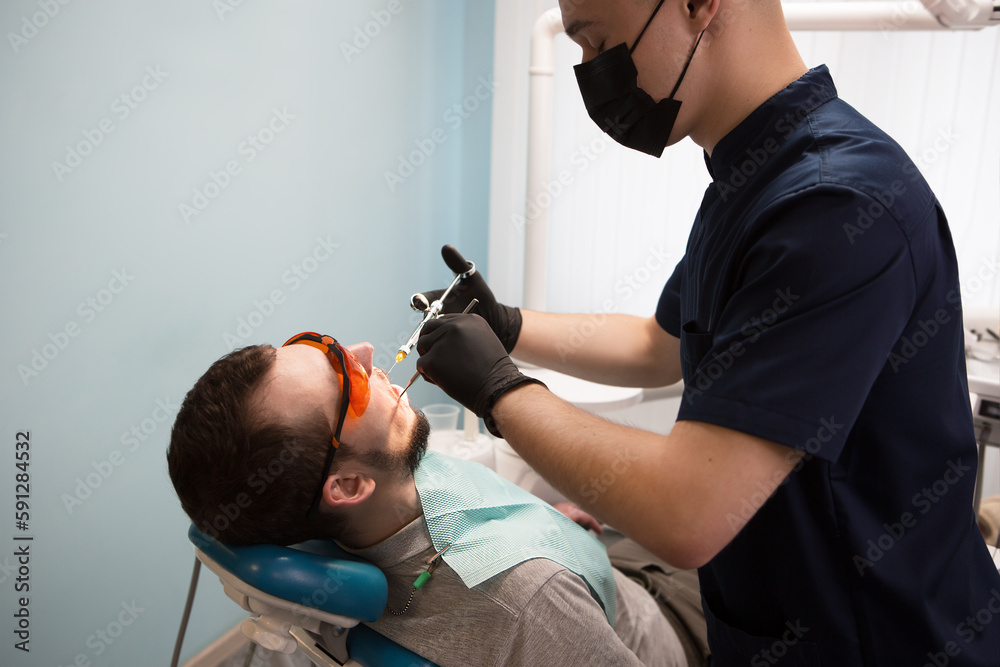 Doctor dentist makes injection anesthesia in the gum to a patient in a ...