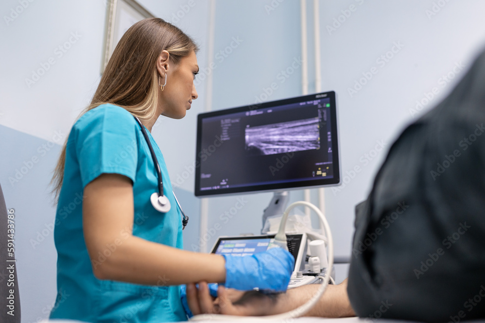 Female doctor doing ultrasound examination of patient's arm veins in ...