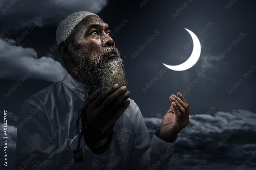 Muslim man with a beard wearing a white cap praying with prayer beads ...