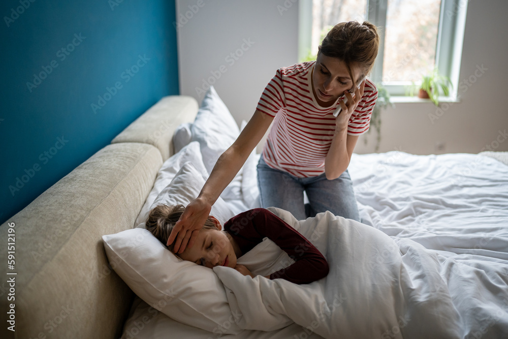 Worried young woman mother calling to pediatrician while sitting near ...
