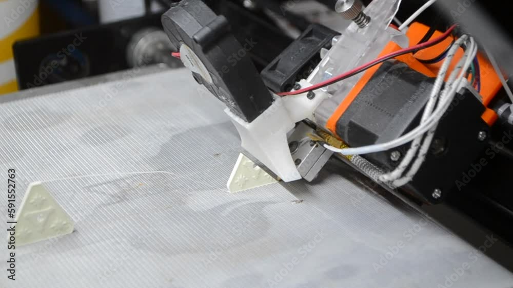 3D printer. 3d printer printing close-up. Molten plastic flowing out of extruder and forming ...