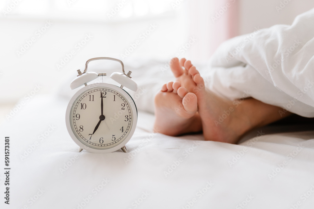 Feet of little girl on bed under white blanket, sleep at morning, focus ...