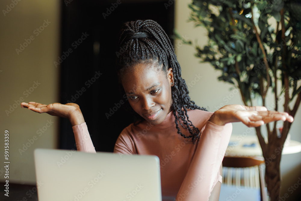 Portrait of young confused African-American woman with long dark braids ...