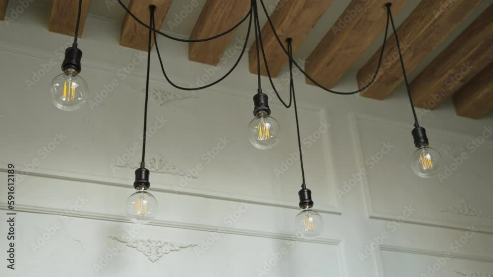 Filament glass bulbs in black sockets hang from loft style wires ...