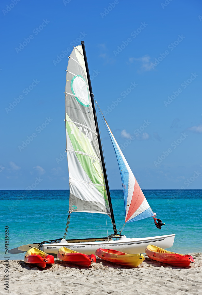 Sail boat, catamaran, with four canoes on tropical beach with blue sky ...